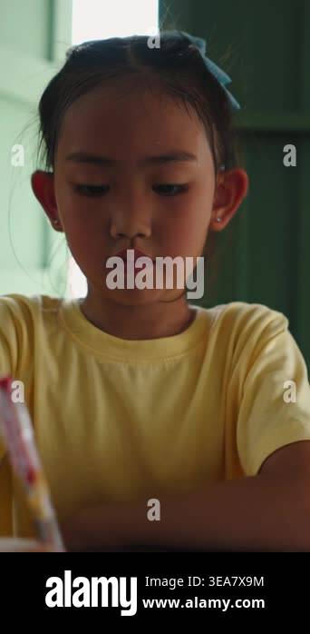 Cute elementary school girl concentrating on her homework, writing and ...