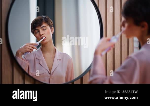 Cheerful model brushing mouth looking bathroom mirror. Closeup happy ...