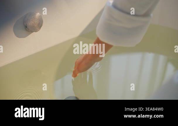 Hand touching bathtub water preparing spa procedures closeup ...