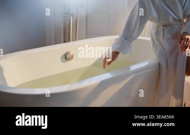 Hand testing bathtub water preparing spa session closeup ...