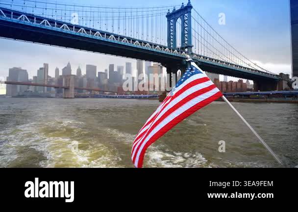 US flag waving near Manhattan Bridge over East River. American flag in ...