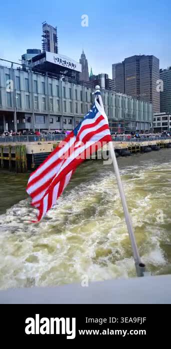 American flag waving on boat leaving New York City pier. US flag in ...