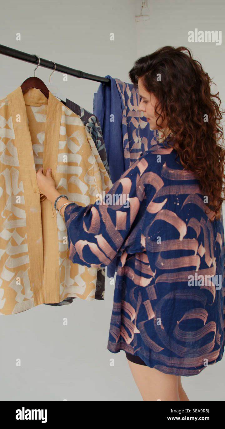 Model showcases unique fashion designs while organizing garments Stock ...