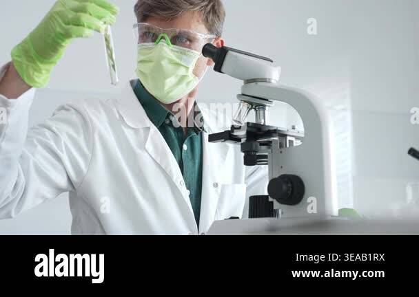 Adult male laboratory researcher wearing green protective gear ...