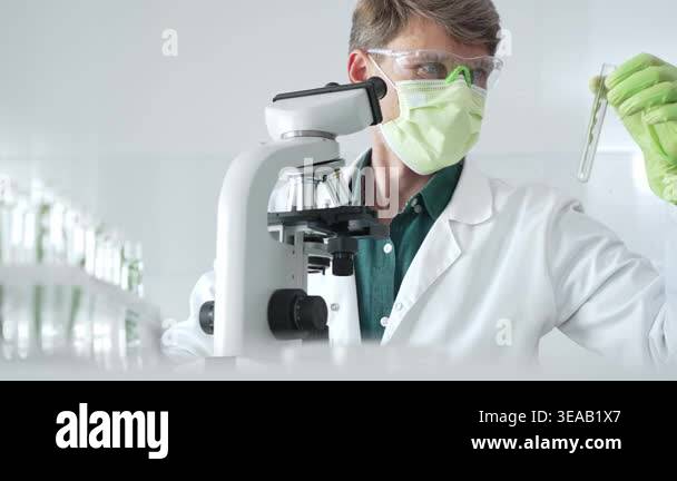 Adult male laboratory researcher wearing green protective gear ...