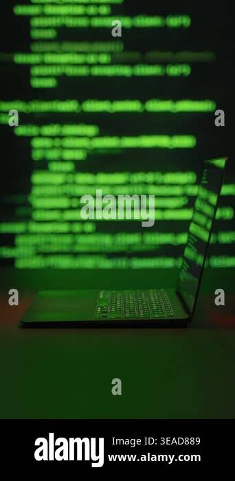 Laptop in dark room with glowing green programming code projected ...