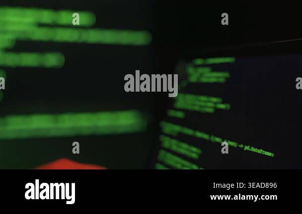 Anonymous hacker in hoodie working on computer with glowing green code ...