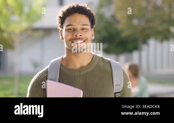 Handsome young male student with a backpack and notebook smiling at the ...