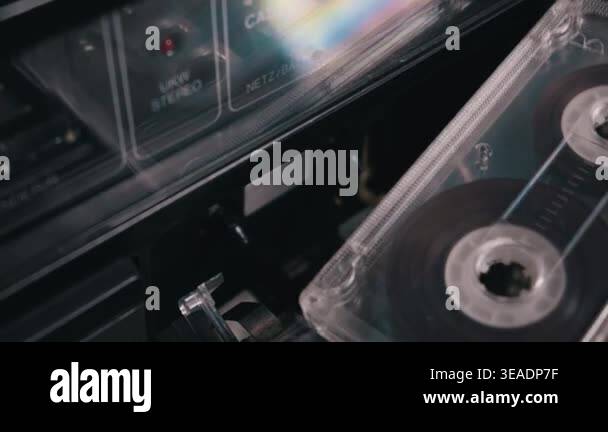 A transparent audio cassette tape rests inside the open compartment of ...