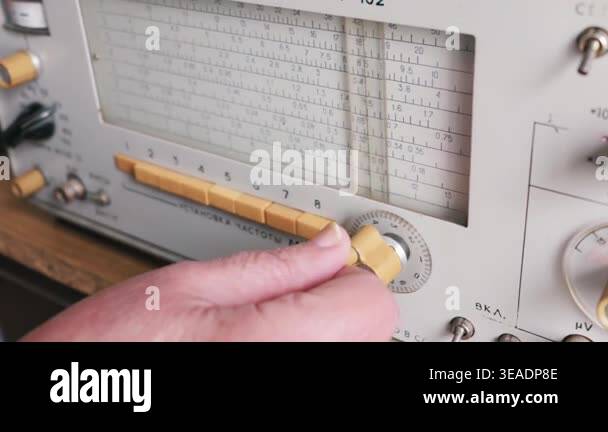 A person hand turns a yellow dial to adjust the tuning frequency on an ...