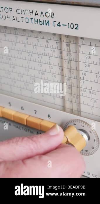 A person hand turns the yellow tuning knob on a vintage analog high ...