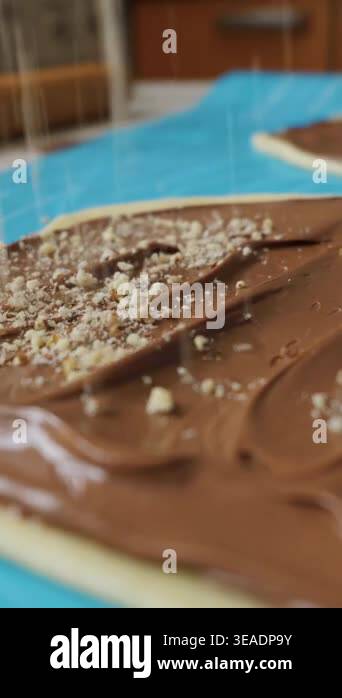 Chopped nuts fall onto a thick layer of sweet chocolate spread covering ...