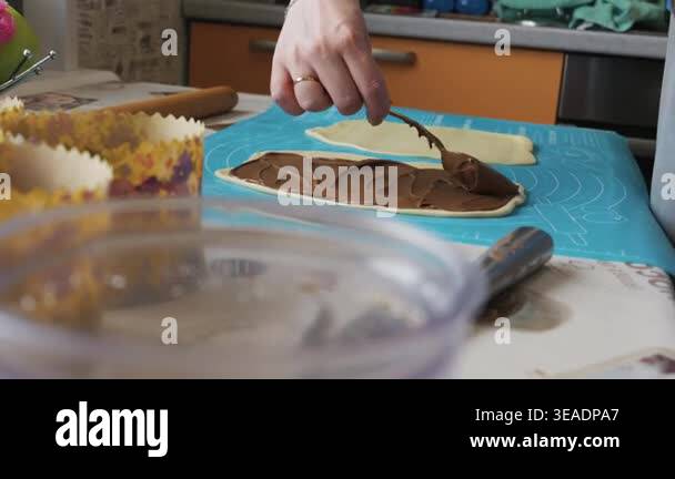 Person hand uses a spoon to spread thick chocolate cream onto raw ...