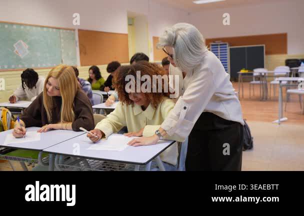 Caring senior female teacher helping a young black student with her ...