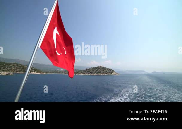 Turkish flag waves from a moving boat over calm blue sea along the ...