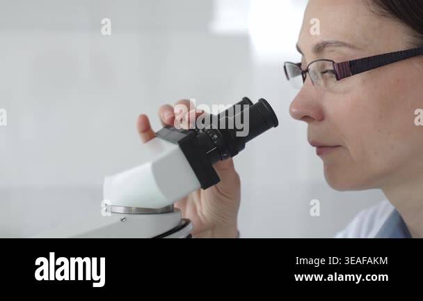 Female scientist adjusting microscope, conducting scientific research ...