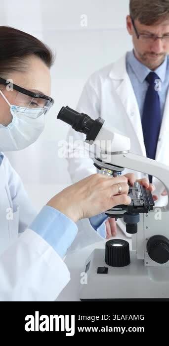 Female scientist wearing protective glasses and mask, is looking ...
