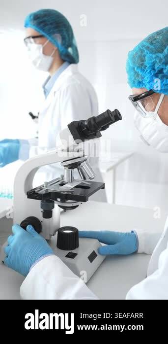 Two scientists in lab coats, face masks, and protective glasses ...