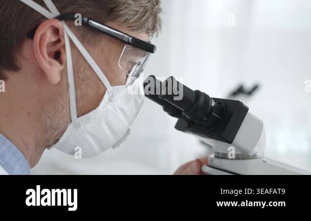 Male scientific researcher wearing protective gear examining sample ...