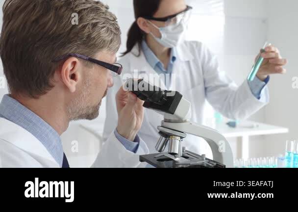 Scientific professional examining specimen through microscope ...