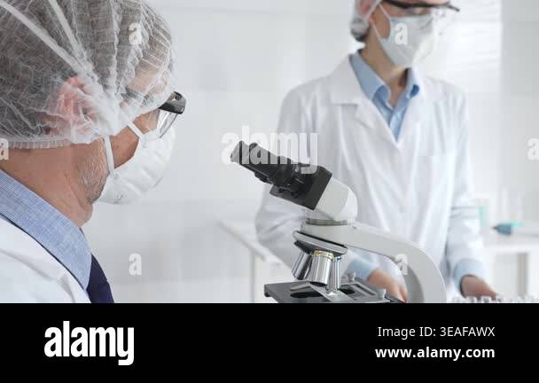 Senior male scientist wearing protective mask, glasses and hairnet ...