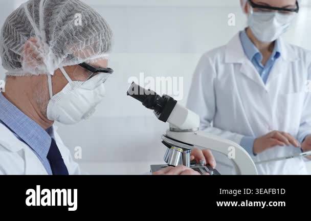 Senior male scientist wearing protective mask, glasses and hairnet ...