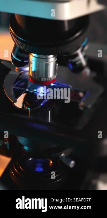 Close up of microscope examining laboratory sample on glass slide ...