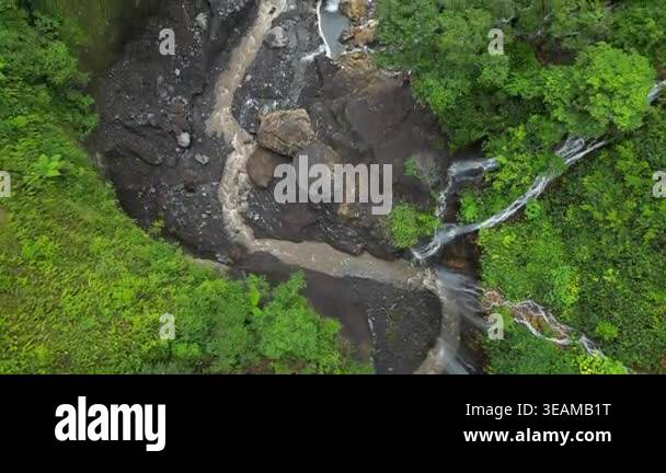 Top-down aerial view of path to Tumpak Sewu waterfall through winding ...