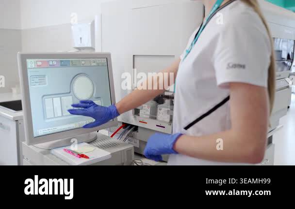 Medical laboratory scientist programming a blood testing machine. A ...