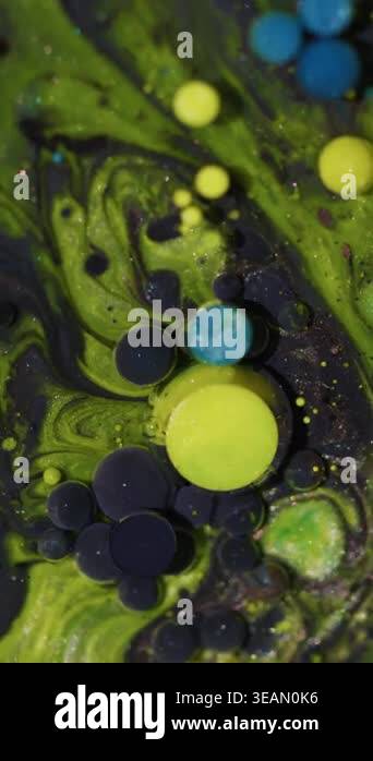 Vertical video. Oil fluid. Ink bubbles. Defocused yellow green blue ...