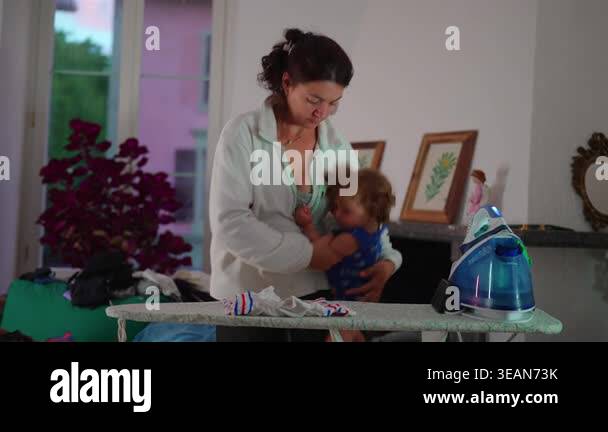 Parent using steam iron on garments while child remains nearby ...
