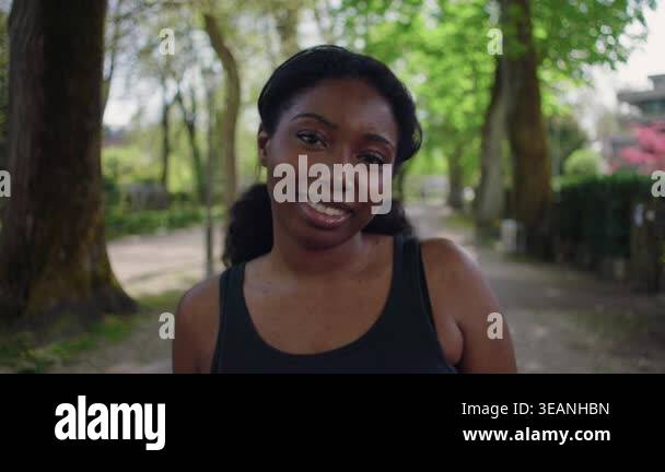 African American woman shows warm smile in outdoor setting surrounded ...