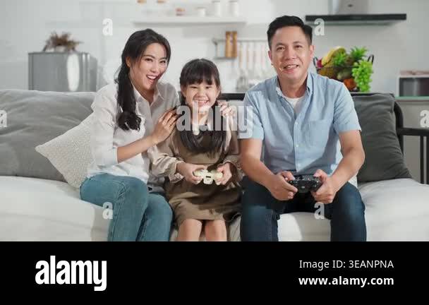 happy family of asian people playing video game together on couch in ...