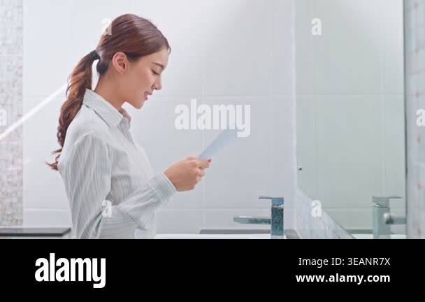 Young woman reading a document while standing in a bright, modern ...