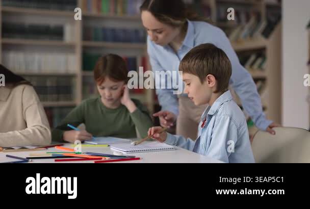 Group of primary school children drawing with pencils on papers during ...