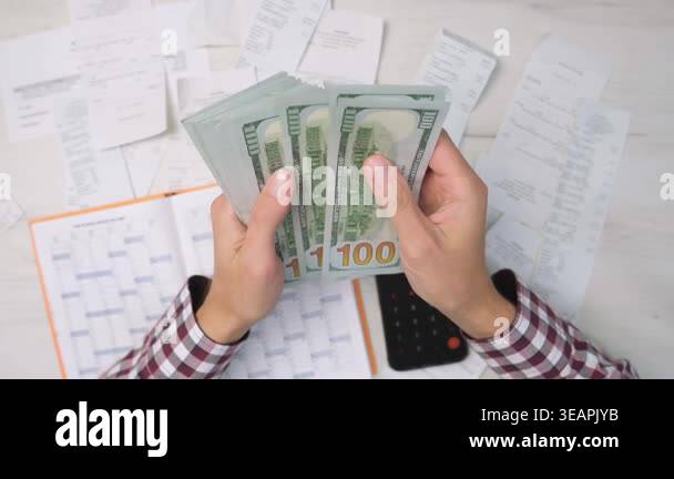 Close up of male hands holding and counting US dollar bills, surrounded ...