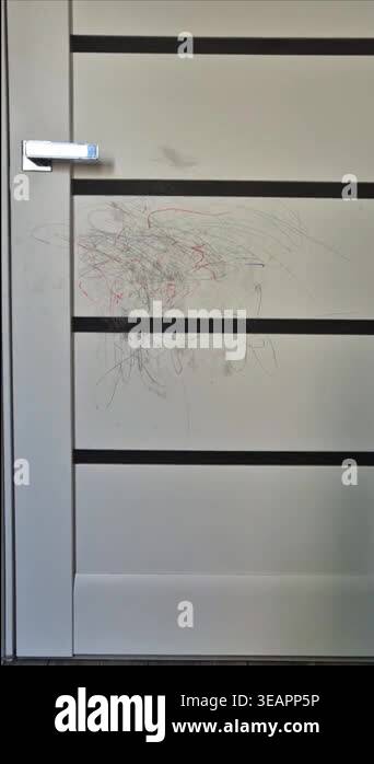 Child drawing with crayons on a white interior door, messy scribbles on ...