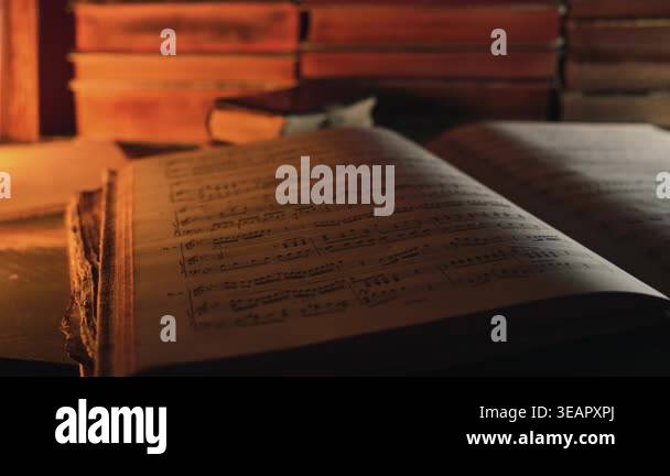 Open sheet music book with musical notes on table in warm light. Close ...