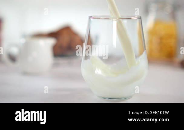 Fresh milk pouring into transparent glass with smooth splash, bright ...