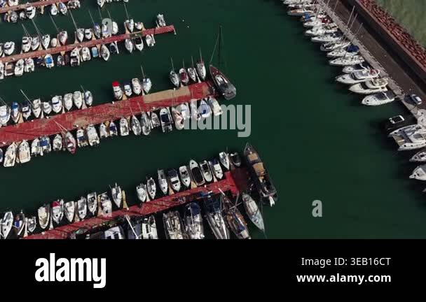 Marina shows many boats lined up on docks. The water is green as ...
