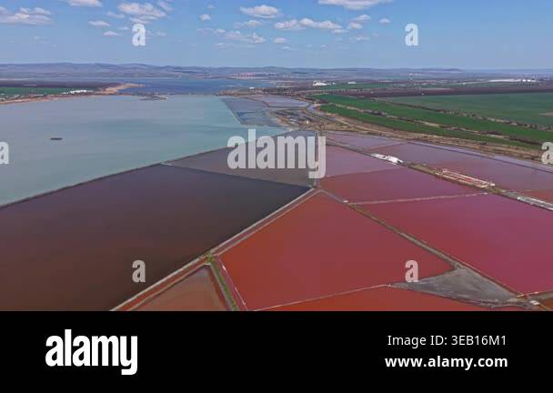 Groups of salt ponds create a patchwork of colors under a clear sky ...