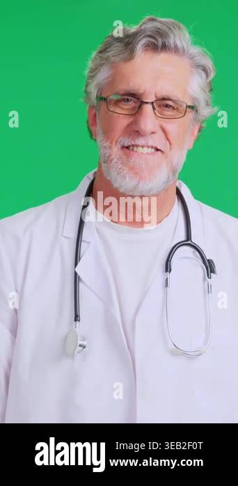 Senior male doctor with a stethoscope smiling and nodding at the camera ...