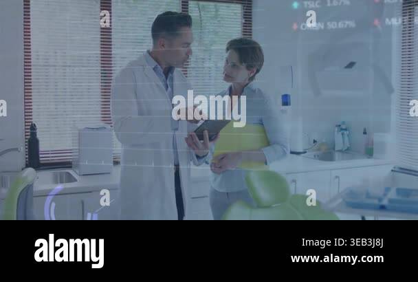 Male doctor pointing at tablet discussing patient data in dental clinic ...