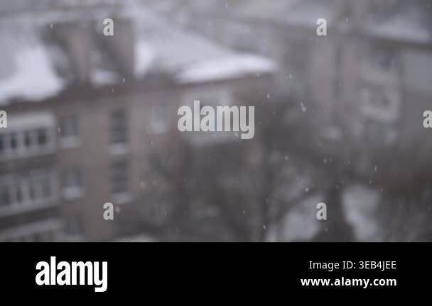 Snowflakes fall in slow motion against a blurred background of city ...