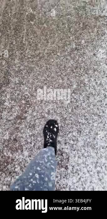 First-person perspective of feet in dark boots walking on snow-covered ...