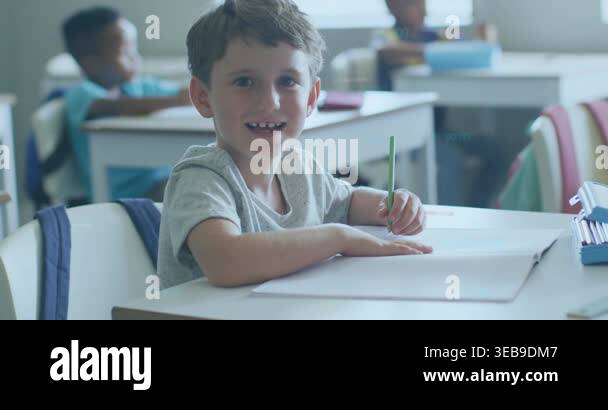 Boy student smiling, holding green pencil above notebook, responding to ...