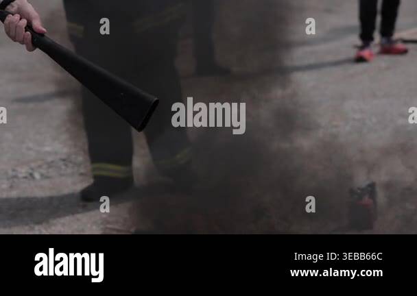 Close-up of a fire extinguisher nozzle spraying CO2 onto a small blaze ...