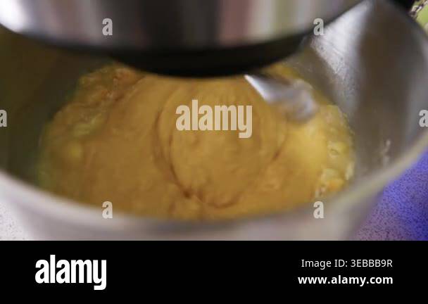 Yellow muffin batter is being mixed inside a professional stainless ...
