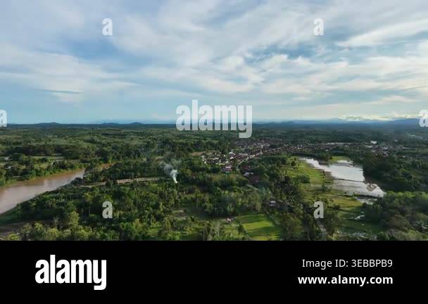 Aerial view of a village with a winding muddy river, its water is murky ...