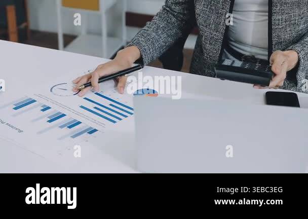 businesswoman holding a calculator and analyzing financial charts at ...